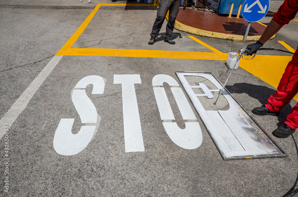 Workers painting asphalt road sign. STOP sign on street. Spraying ...