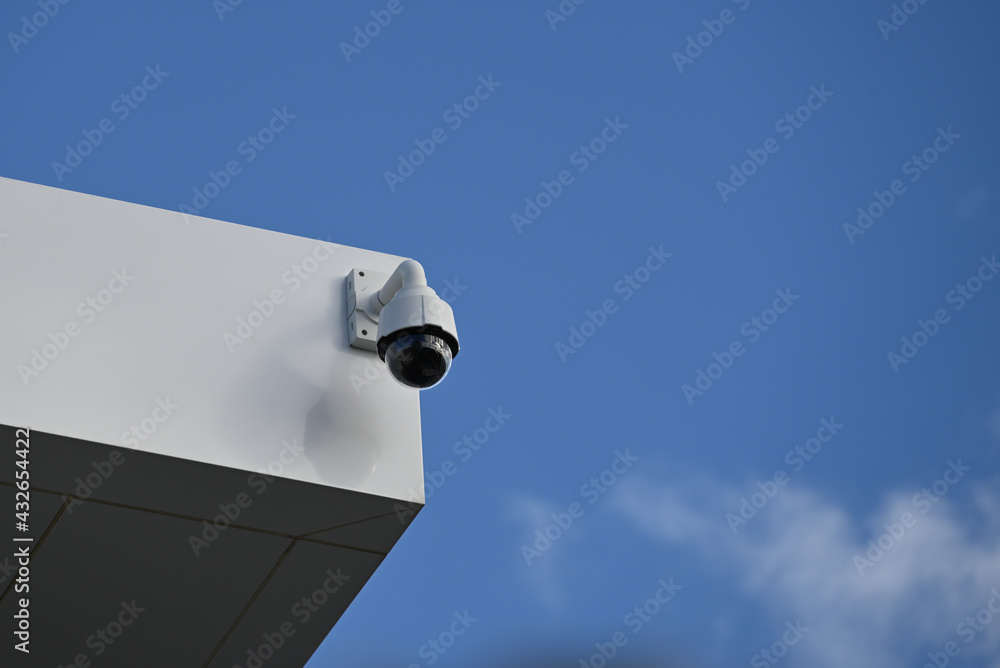 A white dome security camera, part of a CCTV system, attached to a ...