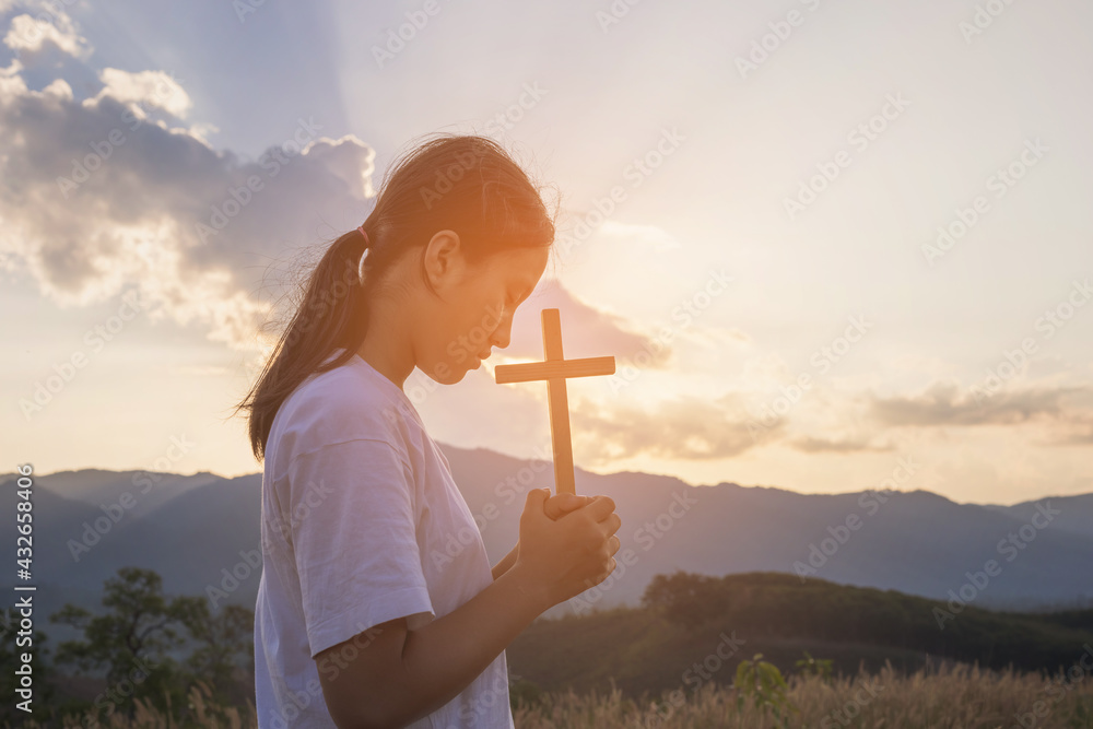 Silhouette of girl praying and holding christian cross for worshipping ...