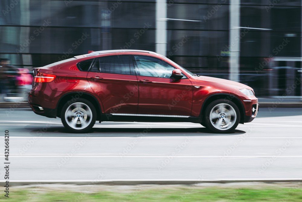 Side view rolling shot with red car in motion. BMW X6 E71 driving along ...