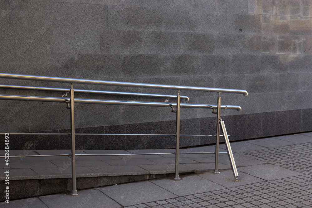 views of the sidewalk, ramp with handrails and a gray wall that ...