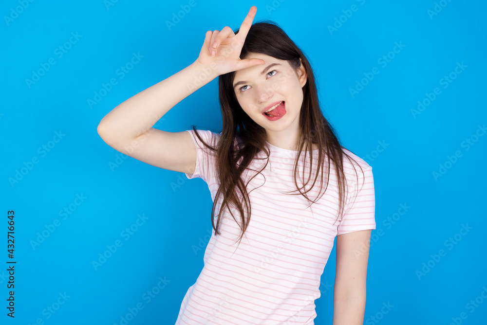 young beautiful Caucasian woman wearing stripped T-shirt over blue wall ...
