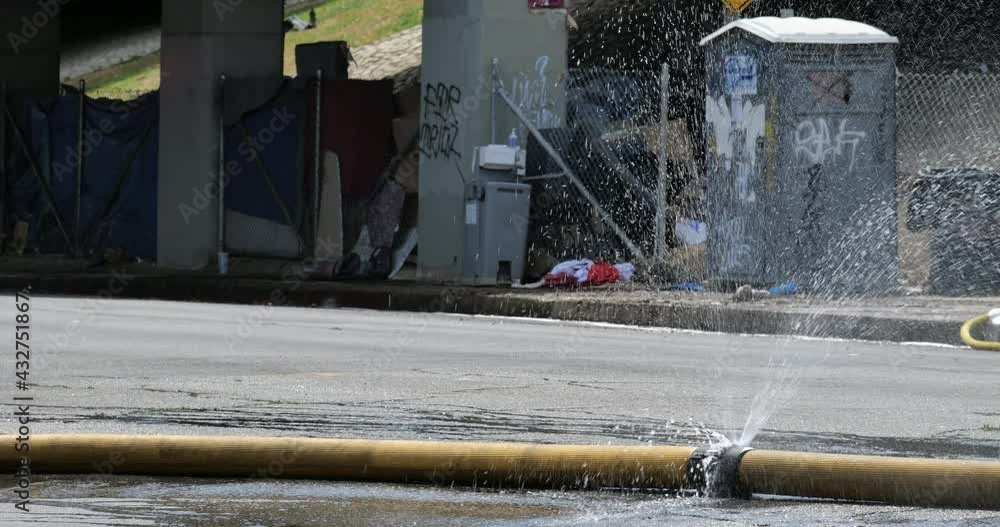 Fire hose from a fire extinguisher spraying water on a city street by a ...