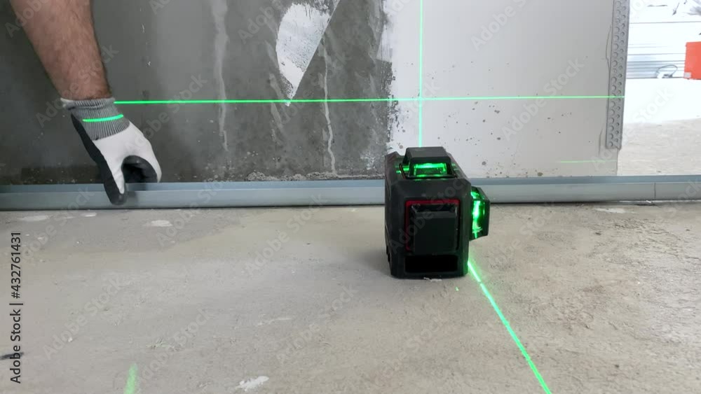Building worker setting modern laser level on the floor on construction ...