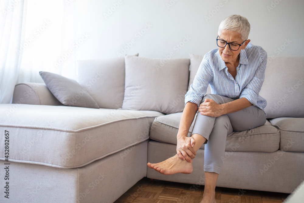 Middle-aged woman suffering from pain in leg at home, closeup. Physical ...