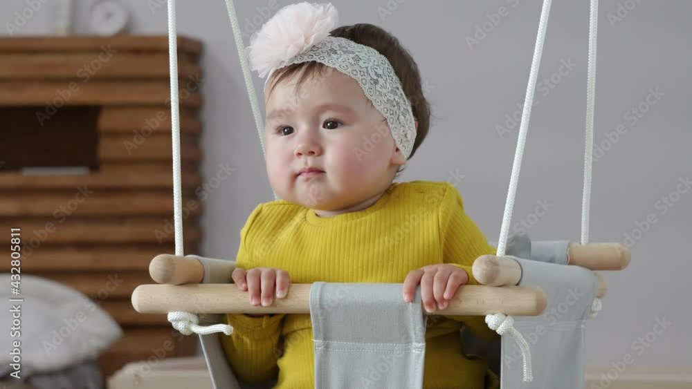 Upset little Baby screams and doesn't want to sit in a doorway swing ...
