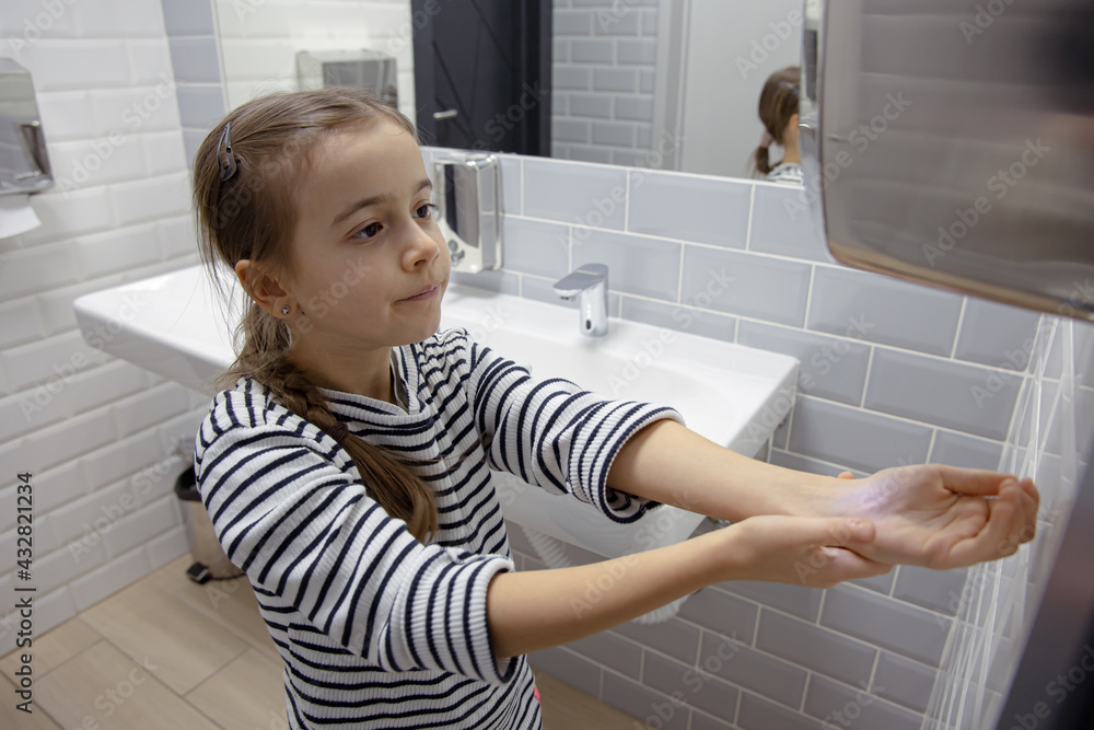 Little girl in the bathroom dries her hands with a hand dryer. Stock ...