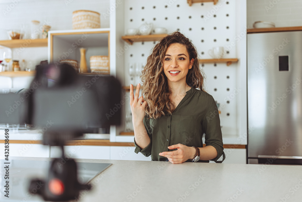 Smiling young woman recording a video at home. foto de Stock | Adobe Stock