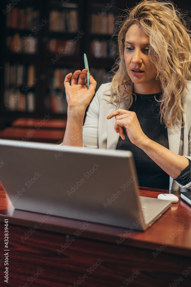 Student using a laptop while studying in a library for her exams Stock ...
