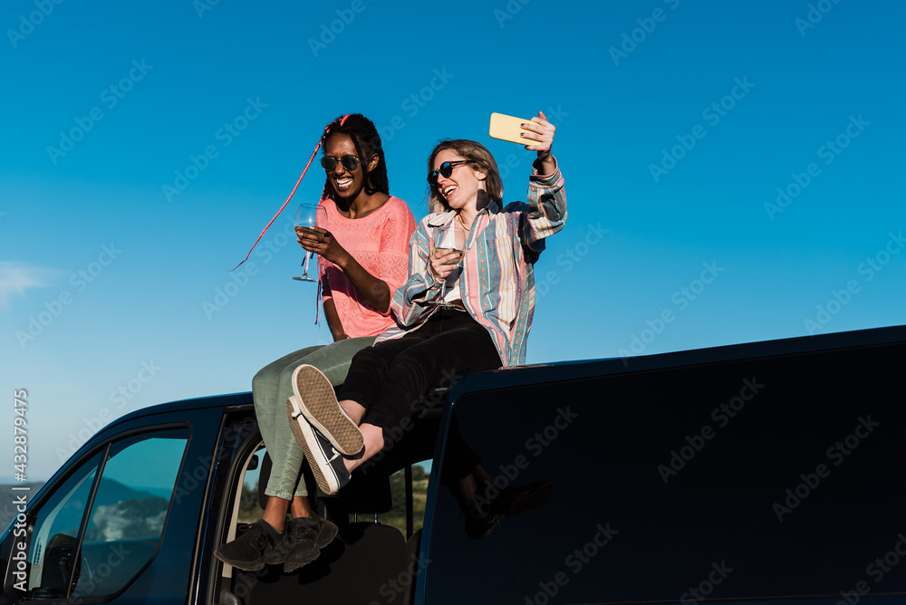 Happy multiracial people sitting on top of camper van roof at summer ...