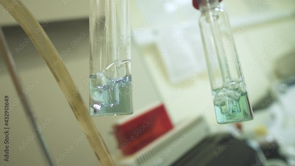 Two glass test tubes are boiling in the laboratory with a blue liquid ...
