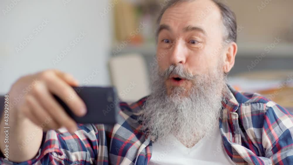 Cheerful Senior Man With Gray Beard And Mustache Having Video Call With