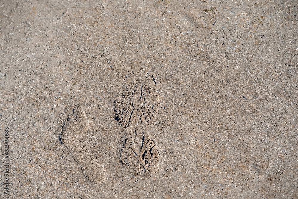 Human bare footprint and shoe print on a sand in nature environment ...