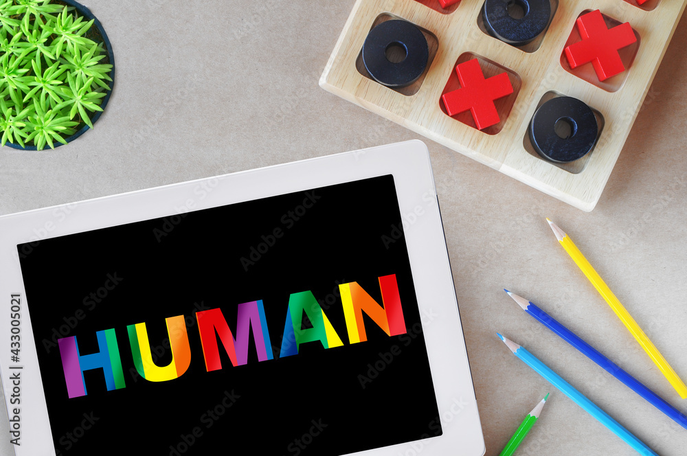 Human word on digital computer tablet with colored pencils and tic tac ...
