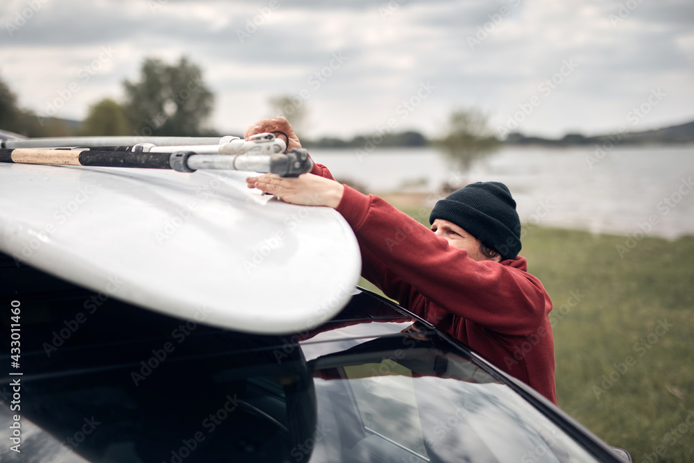 Windsurfer and camper packing and unpacking from a car's roof rack in ...