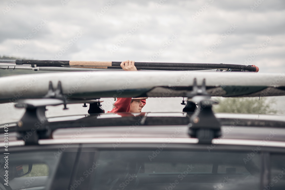 Windsurfer and camper packing and unpacking from a car's roof rack in ...