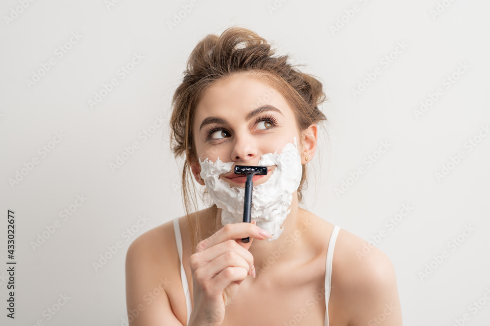Beautiful young caucasian smiling woman shaving her face with razor ...