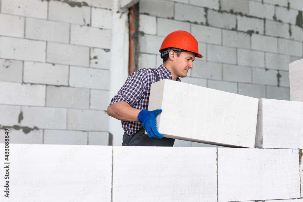 Bricklayer builder working with autoclaved aerated concrete blocks ...