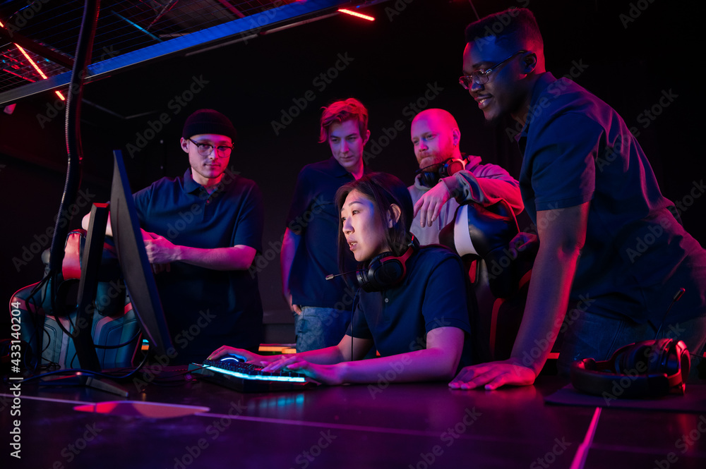 Asian girl playing in a computer club, guys standing behind and ...