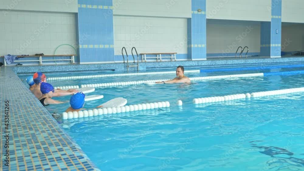 A swimming instructor teaches children to swim in the pool. Caucasian ...