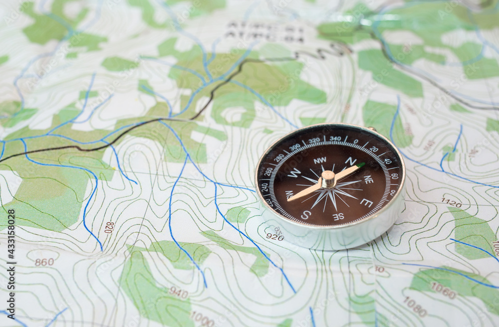 Compass on a physical map, with green details. Travel, exploration and ...
