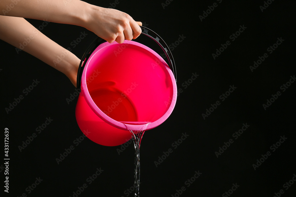 Woman pouring water from bucket on dark background Stock Photo | Adobe ...