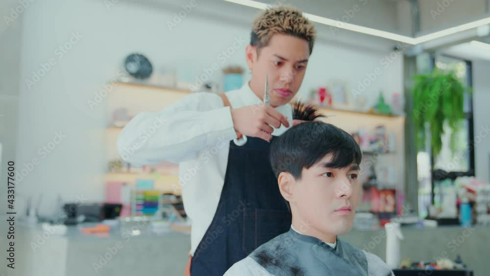 Movement camara. A professional barber Asian man uses scissors and ...