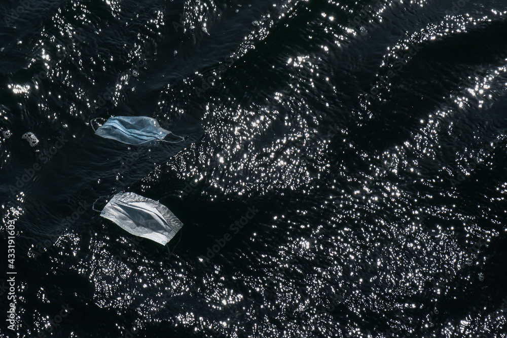 Disposable medical face masks floating in the open water. Biohazard ...