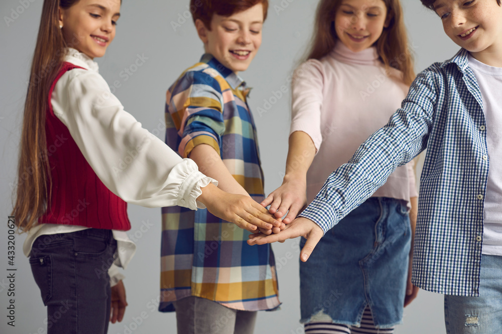 Team of happy children joining hands. Studio group shot of four smiling ...