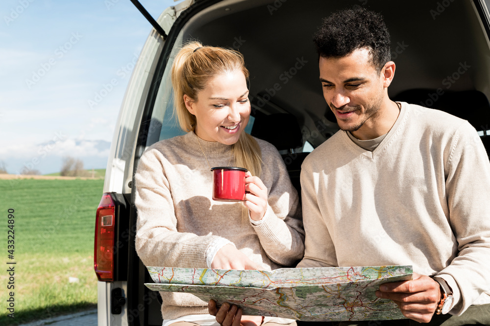 Young couple using a map on a road trip for directions. Young man and ...