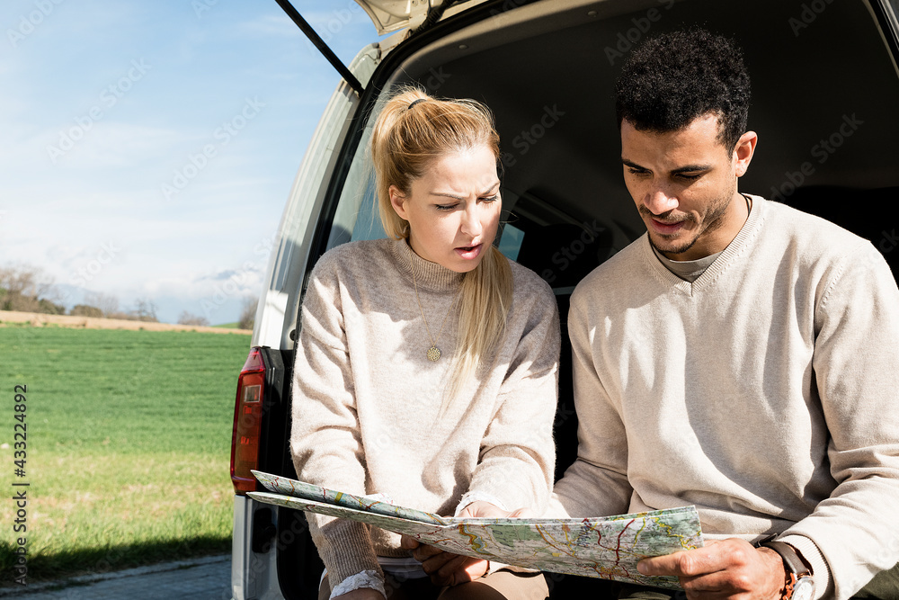 Young couple using a map on a road trip for directions. Young man and ...