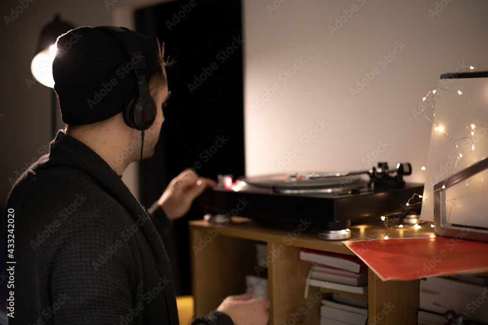 Young unshaven handsome hipster guy push start button on turntable ...