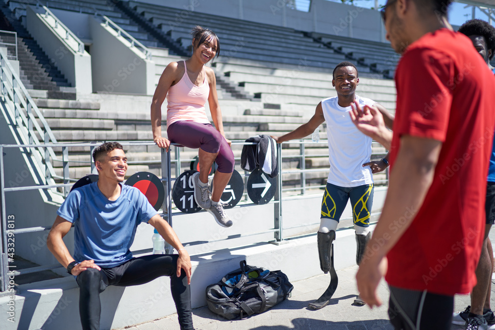 Young athlete friends talking in sunny sports stadium Stock Photo ...
