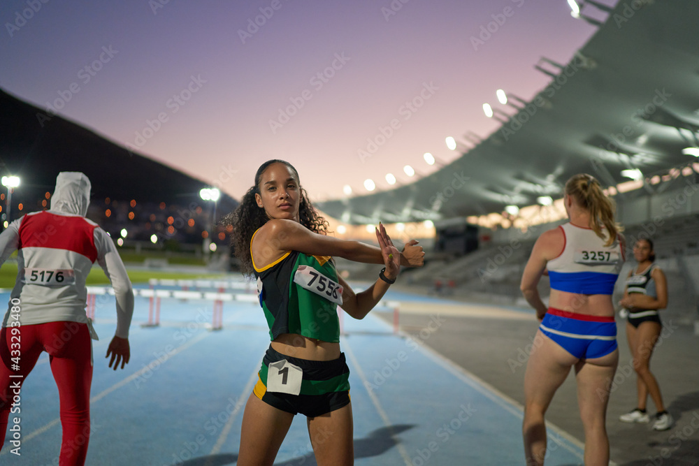 Portrait tough female track and field athlete stretching competition ...
