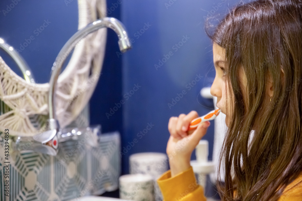 Caucasian girl standing in bathroom and brushing teeth. Focused kid ...