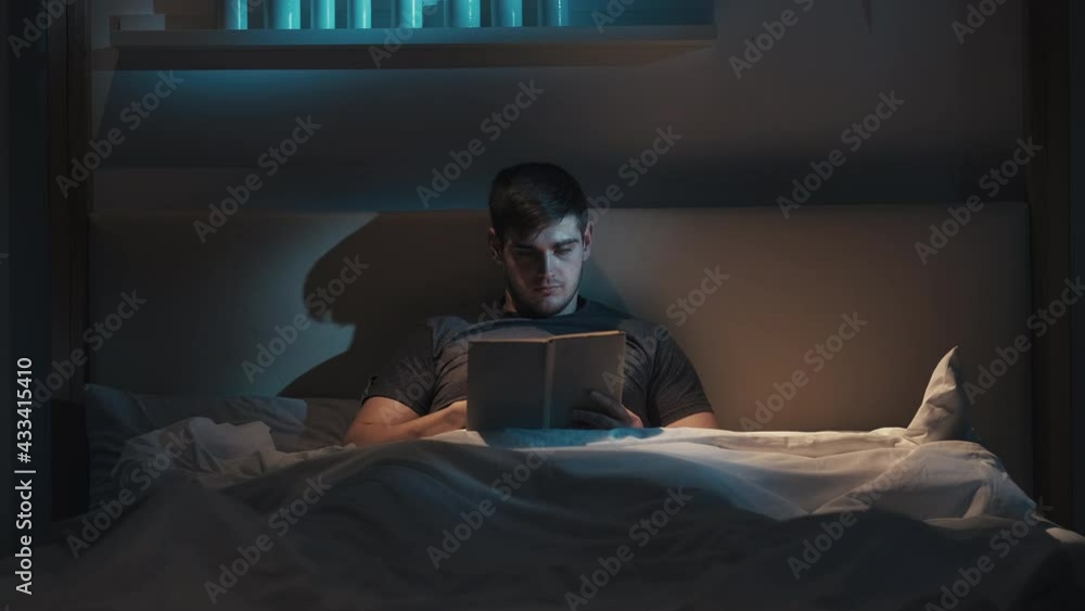 Bed reading. Night fatigue. Home leisure. Tired relaxed man closing ...