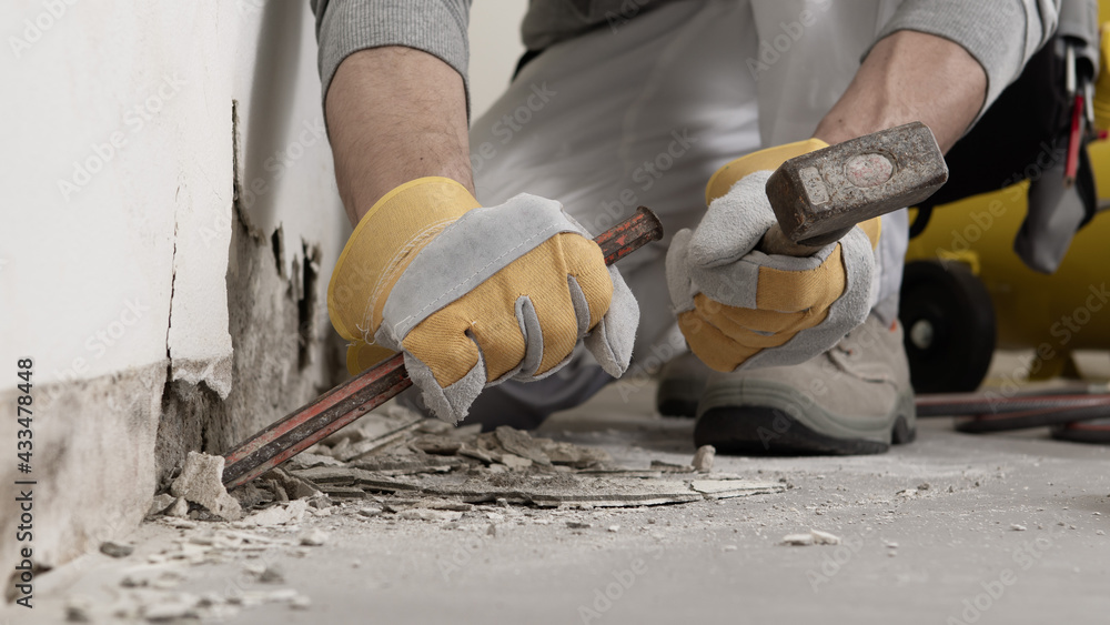 Construction worker hands with gloves working with hammer and chisel to ...