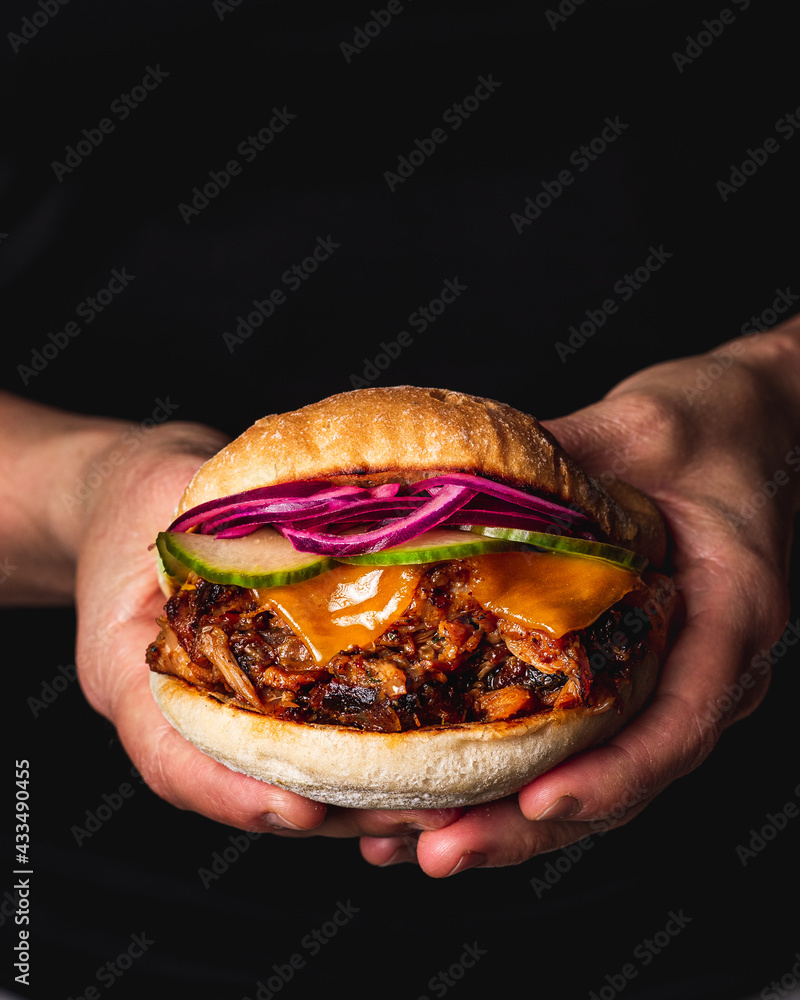 hamburguesa con queso sostenida en las manos sobre fondo negro. ภาพถ่าย ...