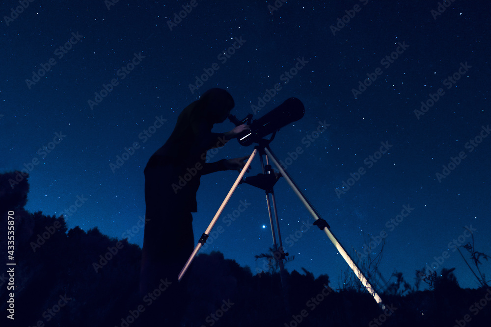 Dark silhouette of a sky watcher of the starry sky in a telescope ...