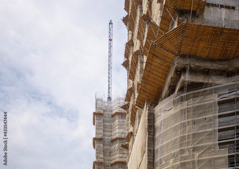 High-rise building under construction with scaffolding and protective ...