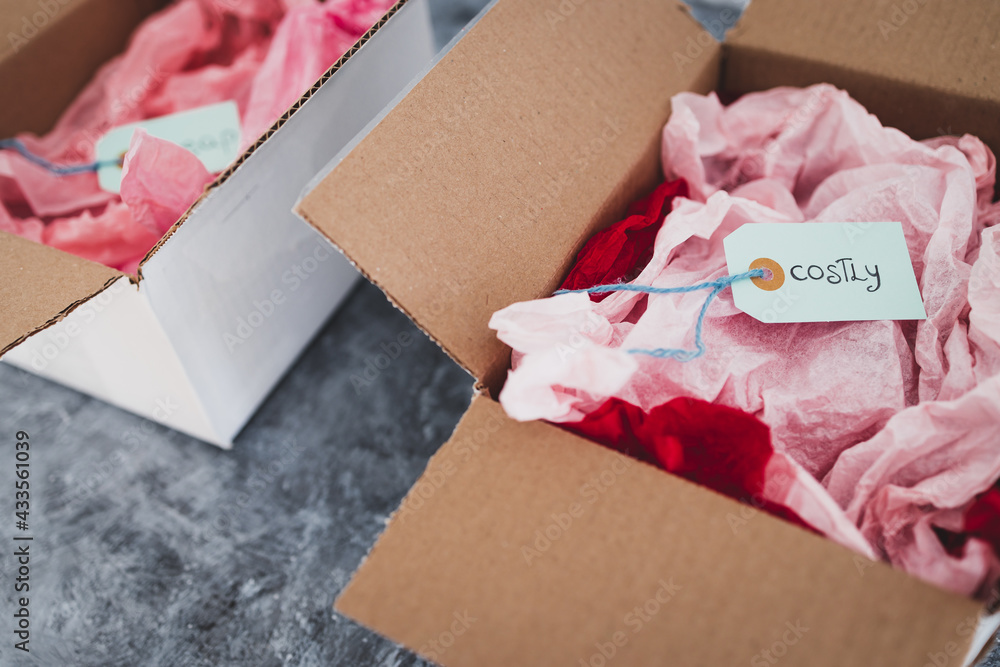 Cheap vs Costly product price tags in two delivery parcels next to each ...