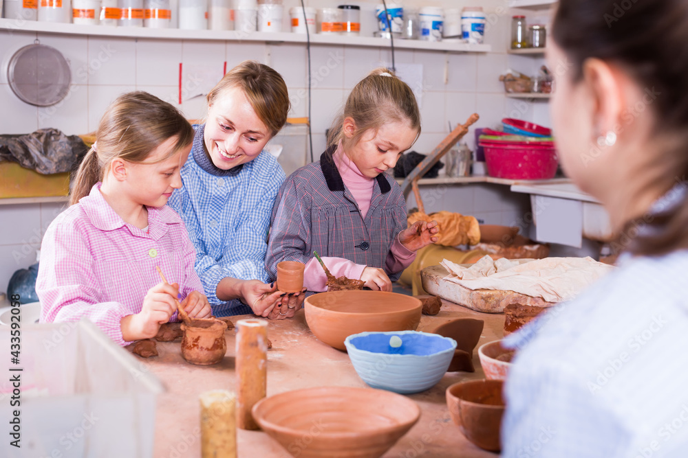 .Young teacher shows the female students how to work with clay in the ...