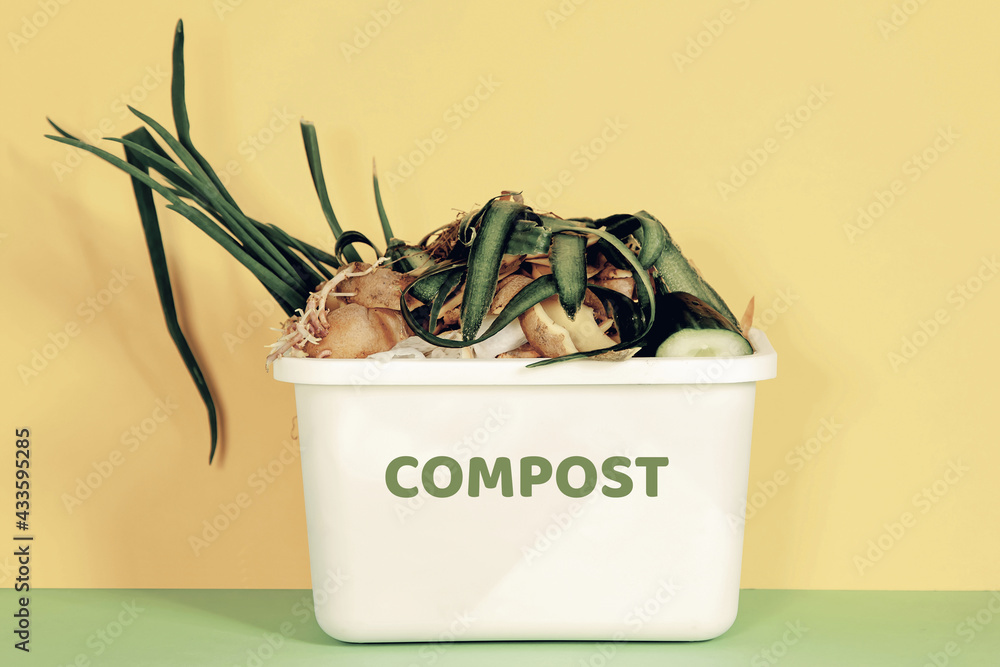 Kitchen composting bin. Peeled vegetables in white compost bin on multi ...