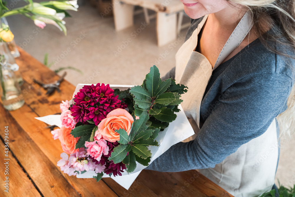 Crop unrecognizable young female florist with long wavy hair in casual ...