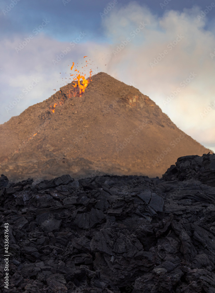 Side view of magma sparks out of the volcano hole and run like rivers ...