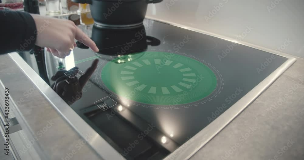 Woman activates futuristic hotplate stove with touch elements and sets ...