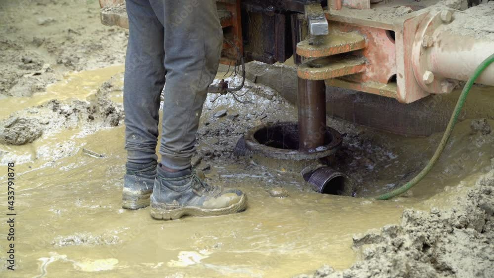 Man legs standing in the mud on a water well drilling process (diging a ...