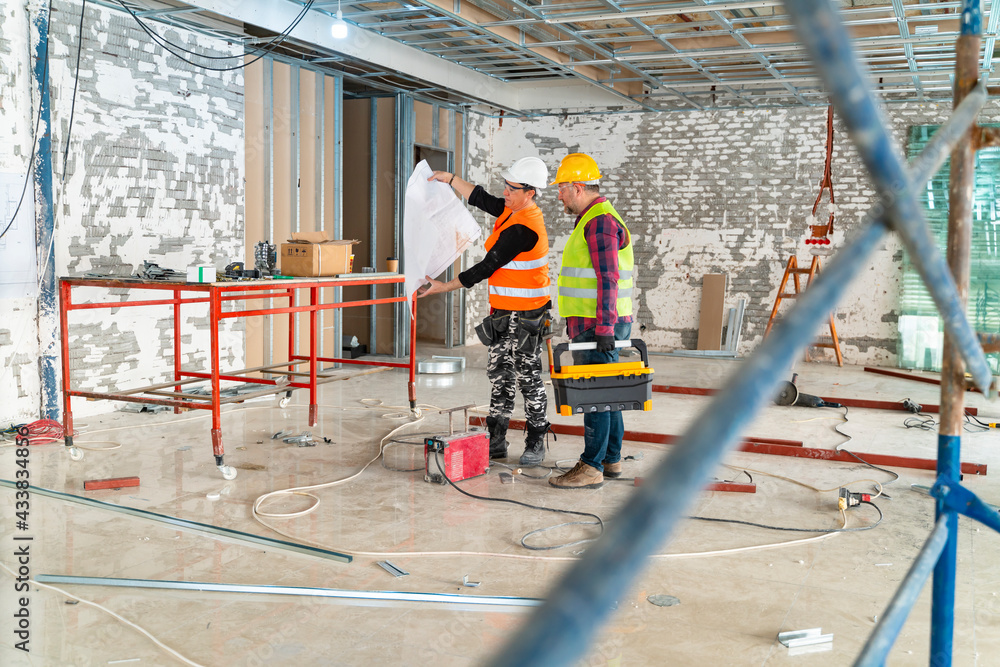 Adult construction workers working on housing plan while at ...