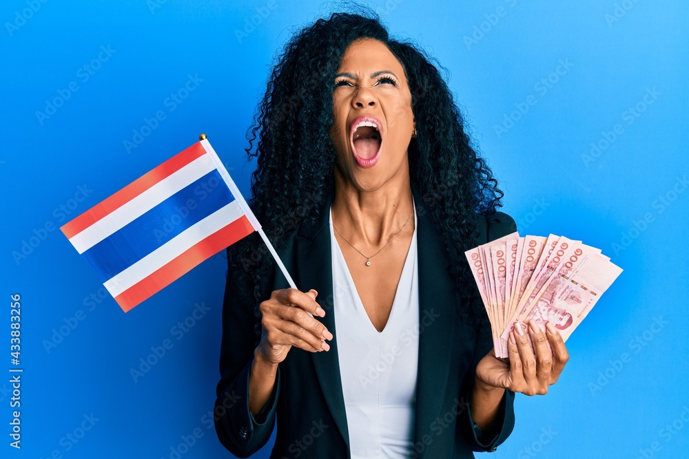 Middle age african american woman holding thailand flag and baht ...
