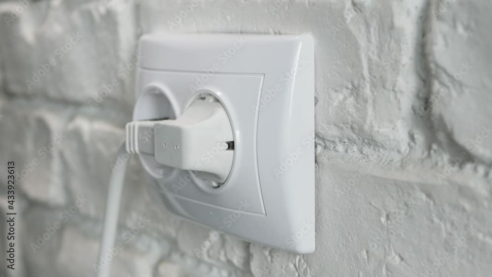 Inserting an Electrical Power Cord into a Socket on the Office Wall ...